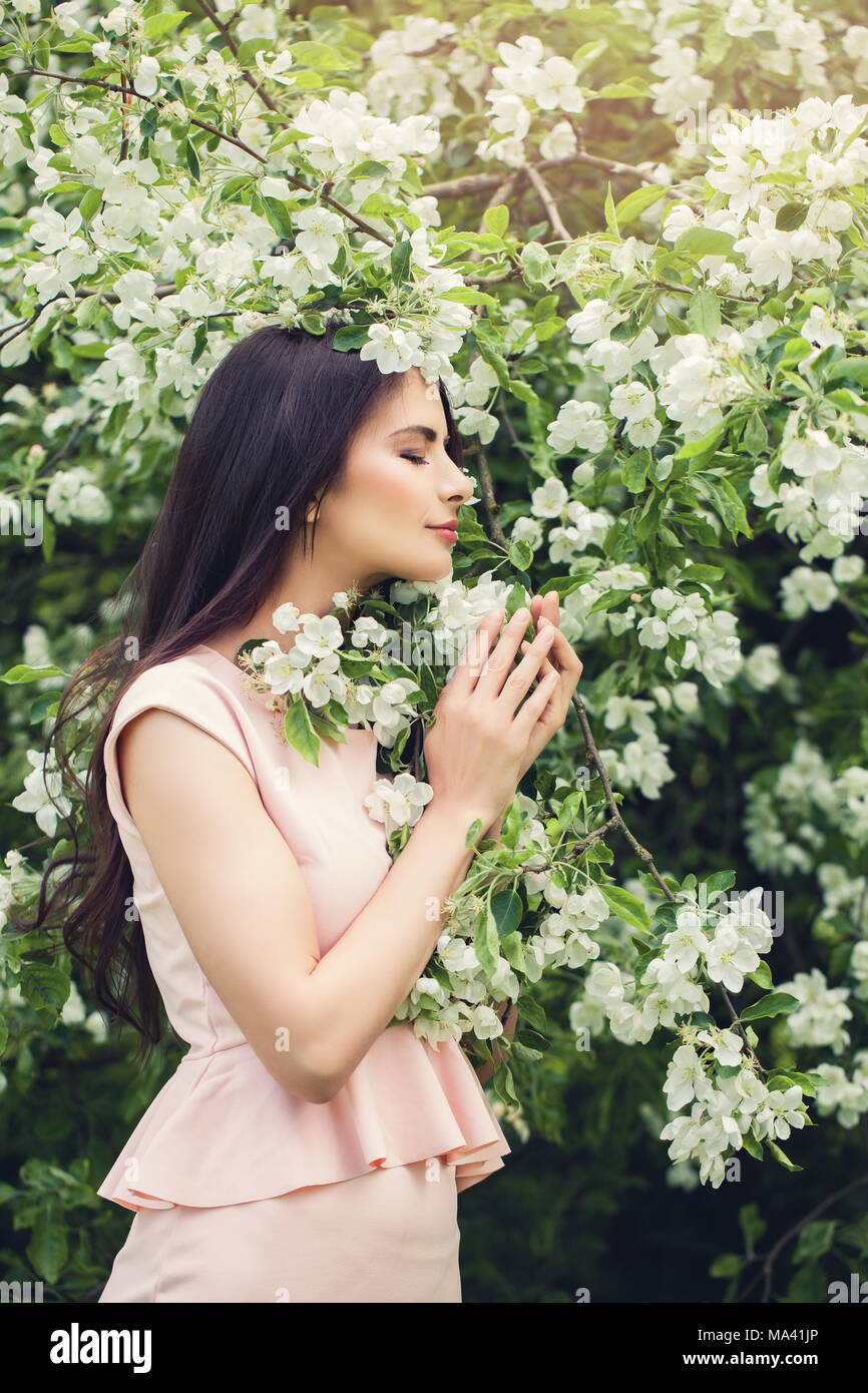 Perfect young woman smelling flower in blossom spring flowers garden ...