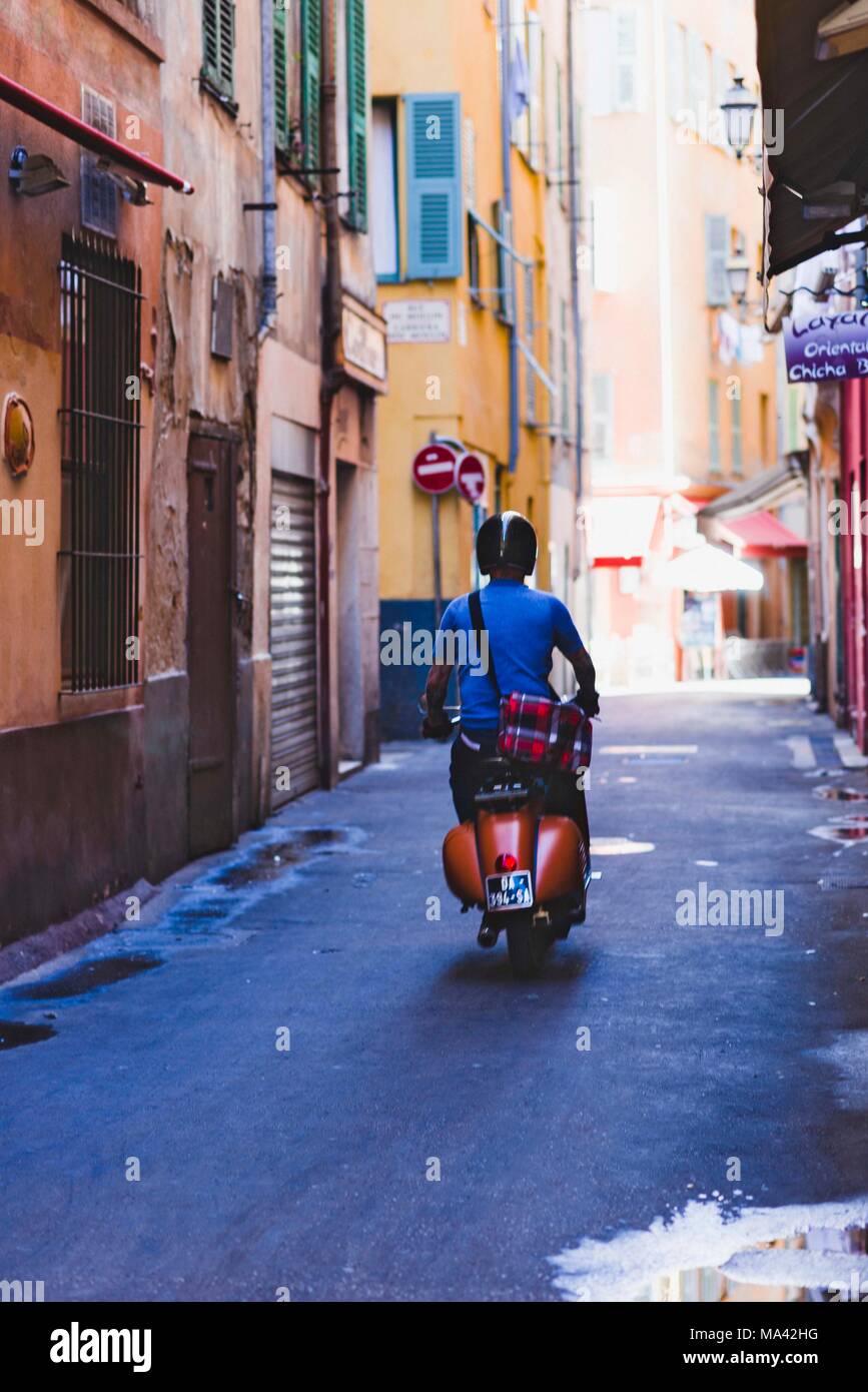 A man riding a Vespa through narrow lanes in Nice, France Stock Photo ...