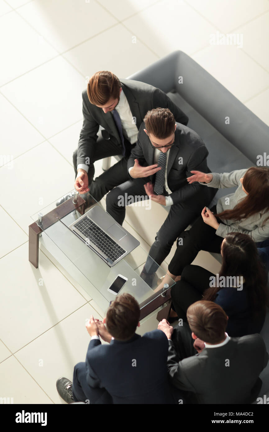 Young business team sitting and standing around the table and sharing ...