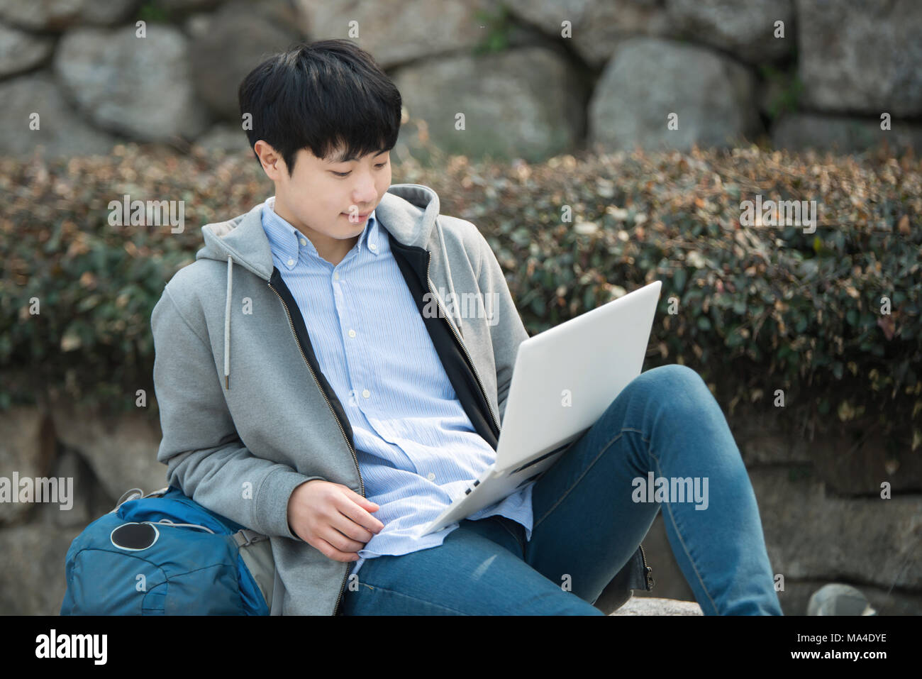 Asian man backpacking using laptop Stock Photo - Alamy