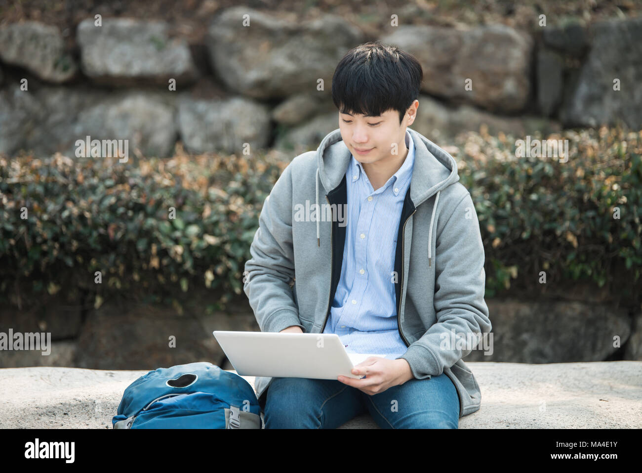 Asian man backpacking using laptop Stock Photo - Alamy