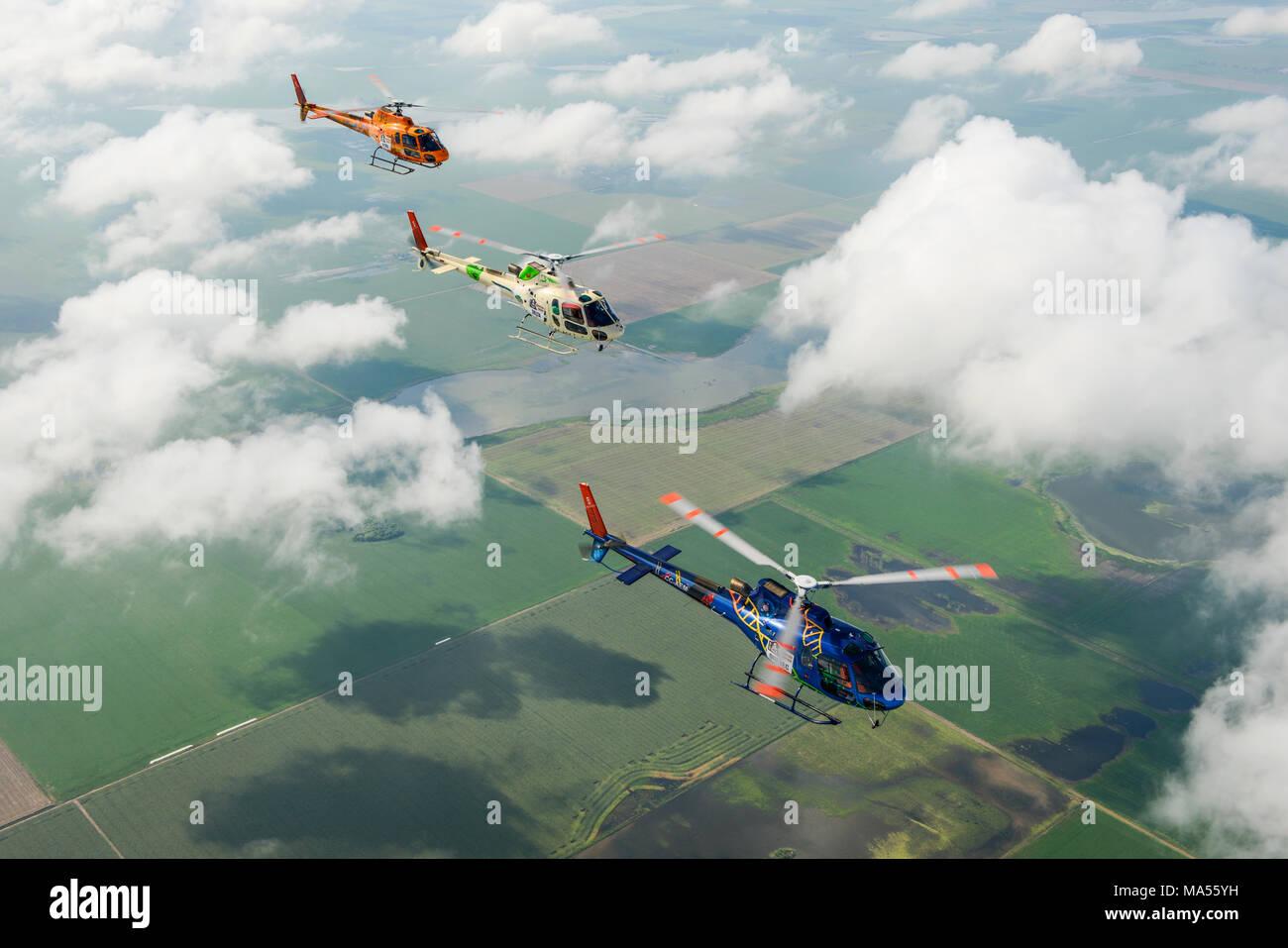 Air to air panorama photo of three lined up colorful Airbus helicopters ...