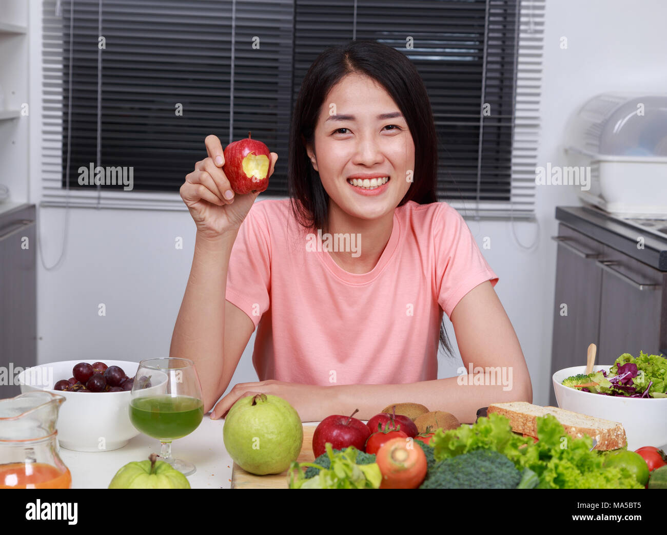 young woman eating red apple in kitchen Stock Photo - Alamy