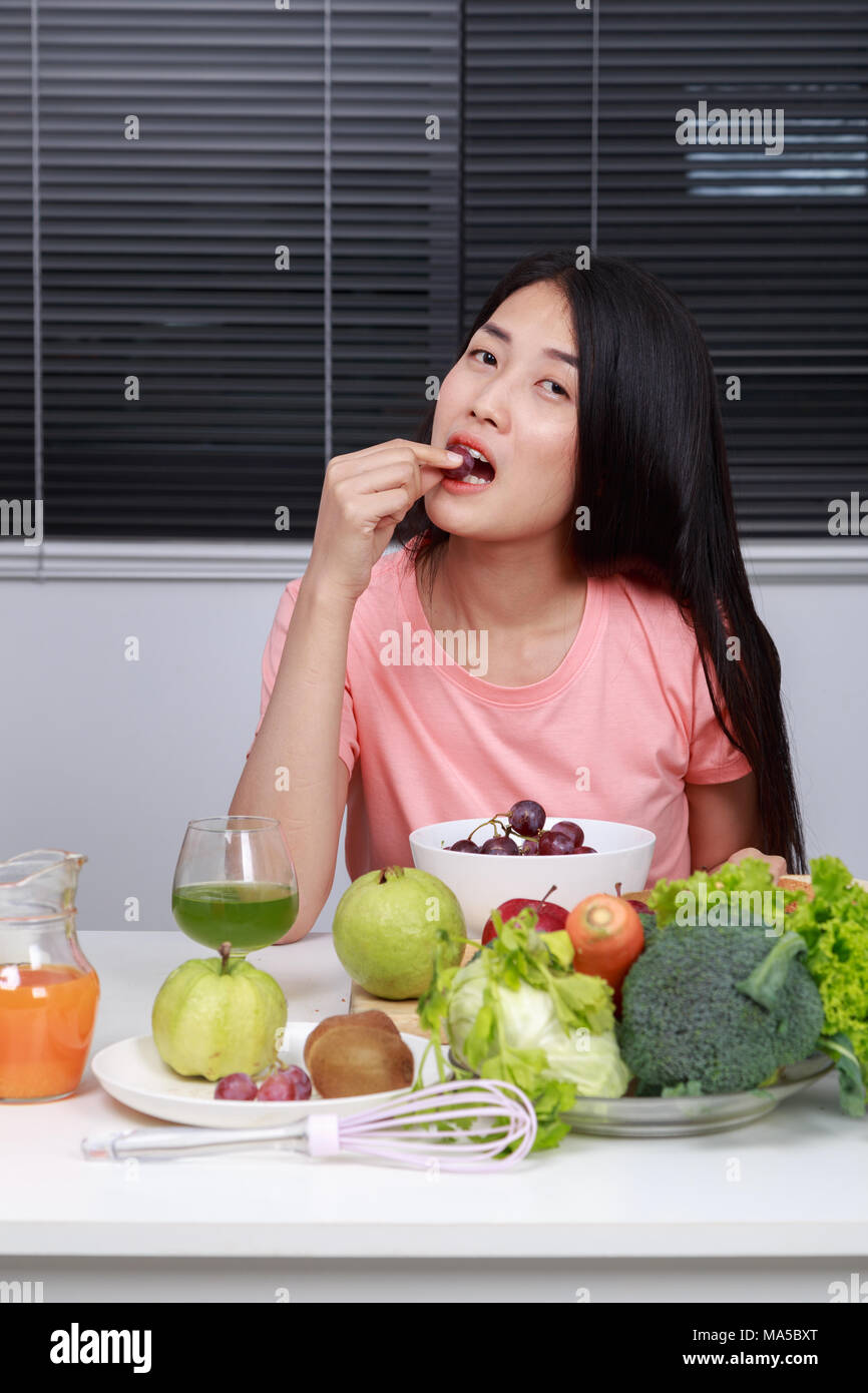 young woman eating grape in kitchen room Stock Photo - Alamy
