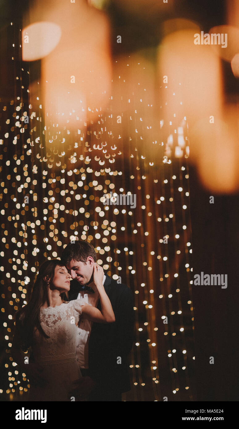 Bridal couple in love, hug, dance, side view, curtain of lights, detail ...