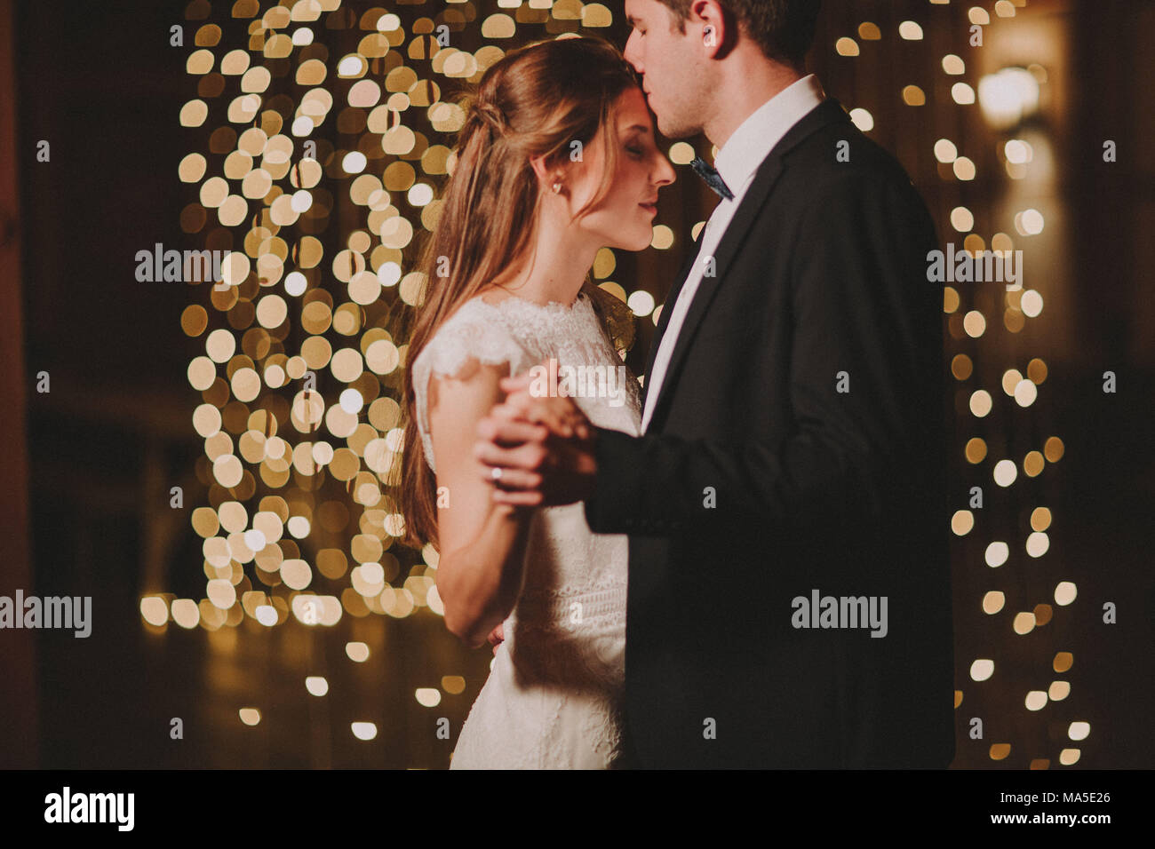 Bridal couple in love, hug, dance, side view, curtain of lights, detail ...