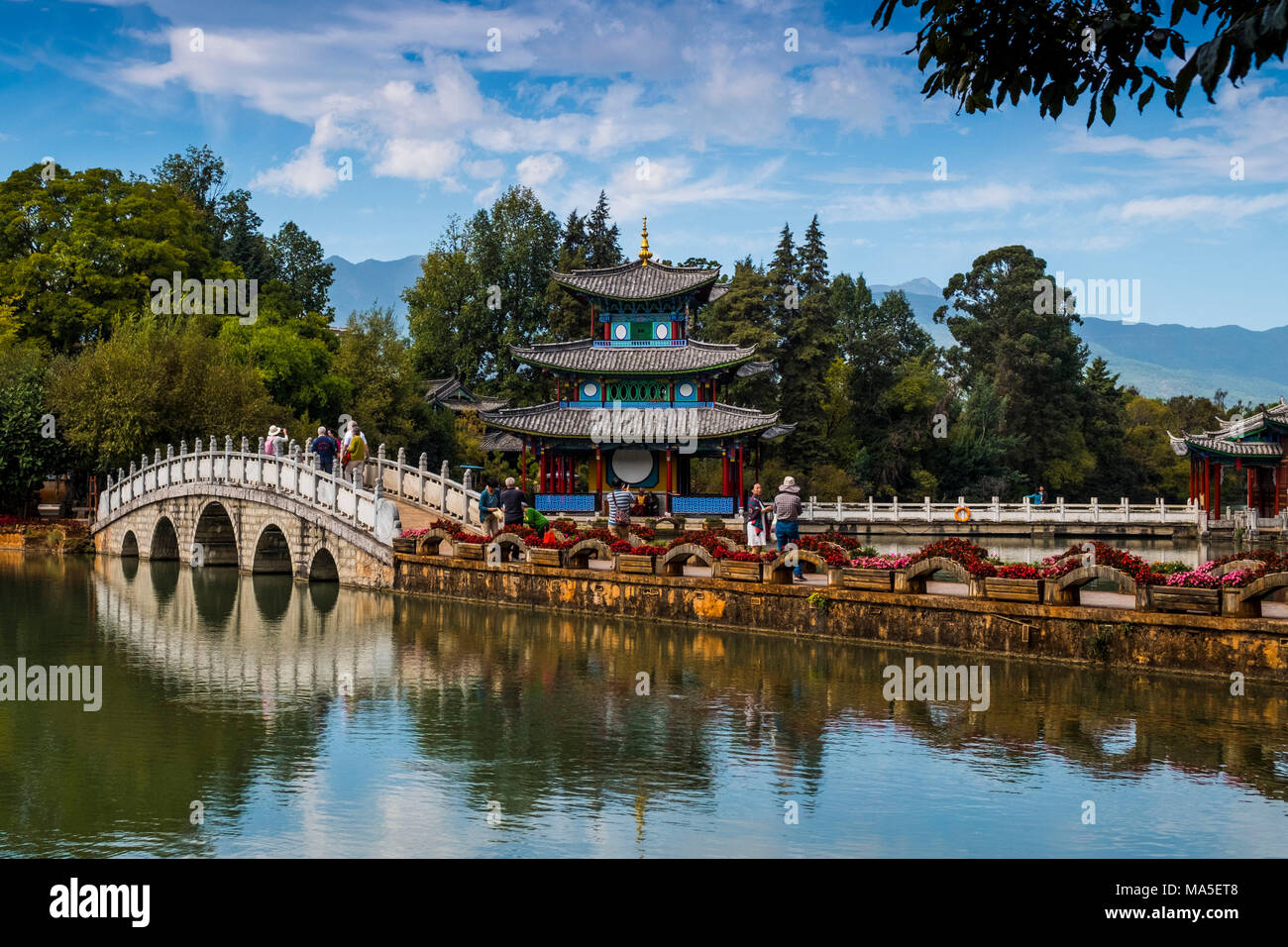 Tourists over arched bridge at Black Dragon Pool, Lijiang, Yunnan ...