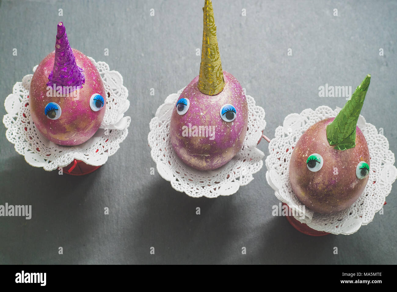 Cute unicorns space cosmic purple crafted easter eggs with colorful horns and toy eyes on white ...