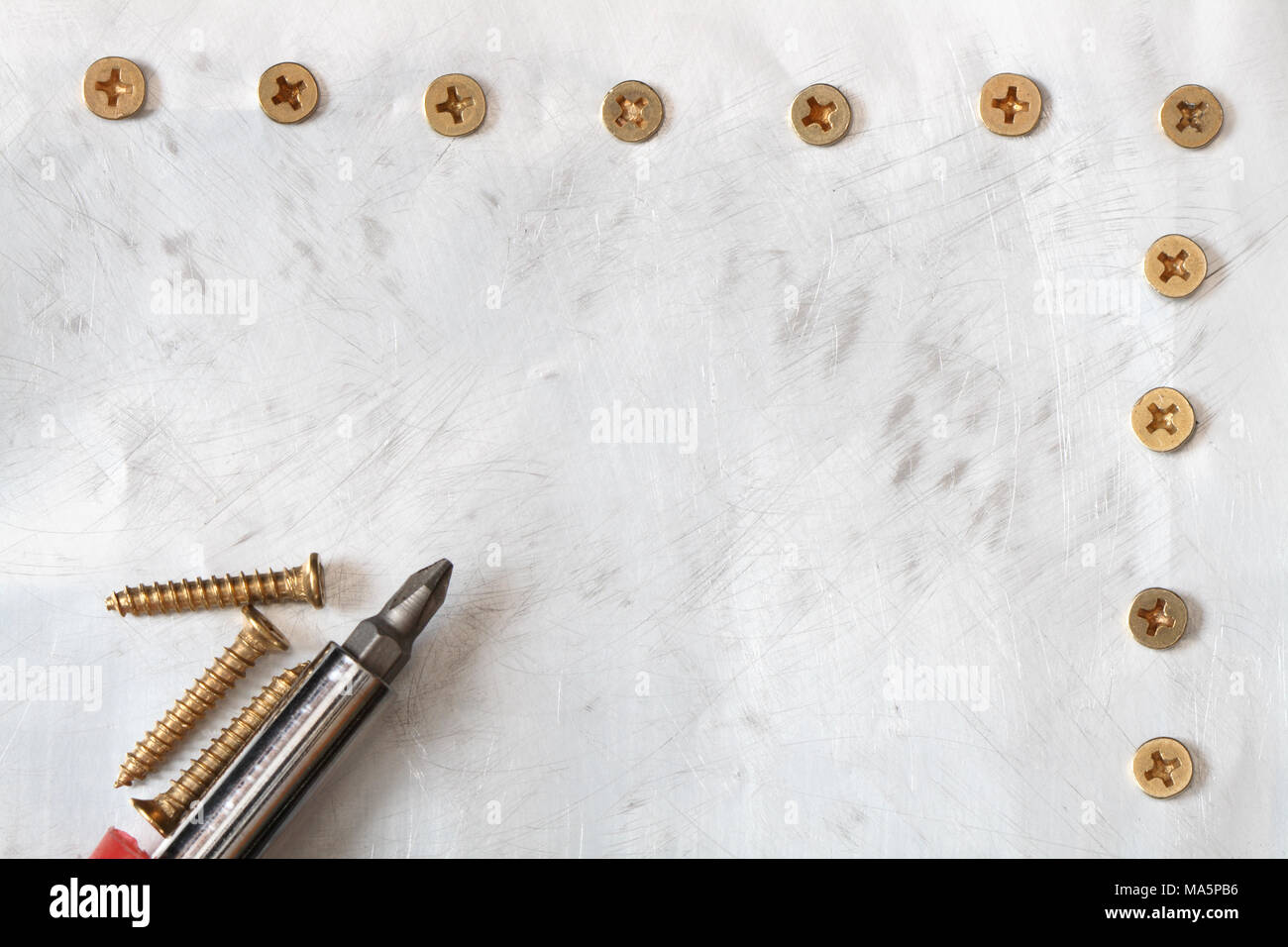 Abstract gray metal background with screws attached and screwdriver ...