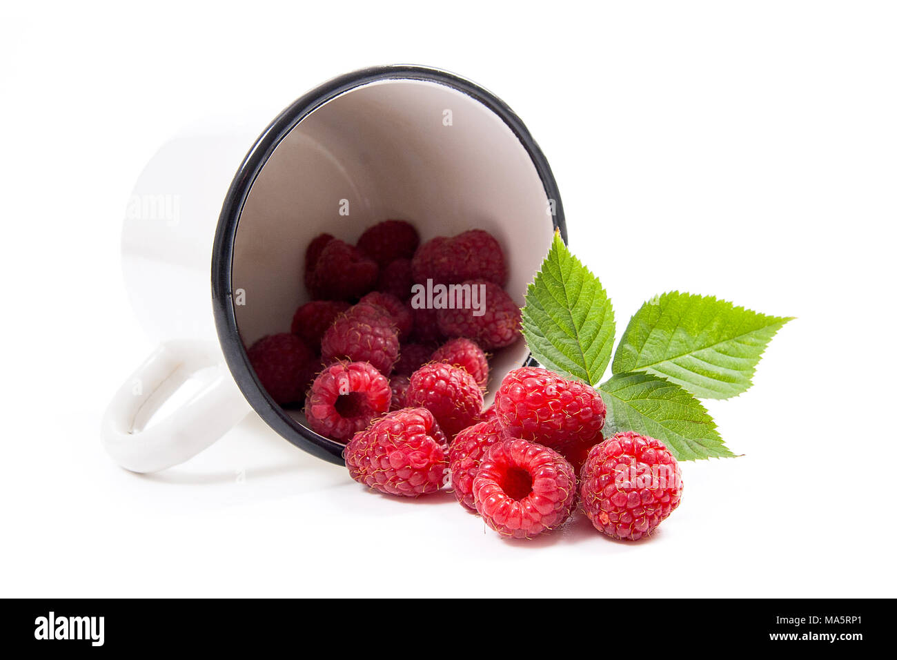 Close up view of white cup with fresh raspberries fruits and big green ...