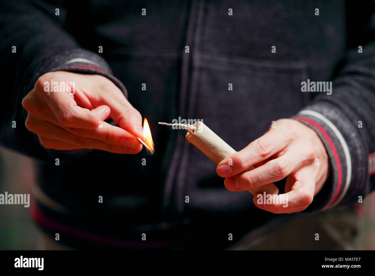 Close up of man hand lighting up a firecrackers in a burred background ...