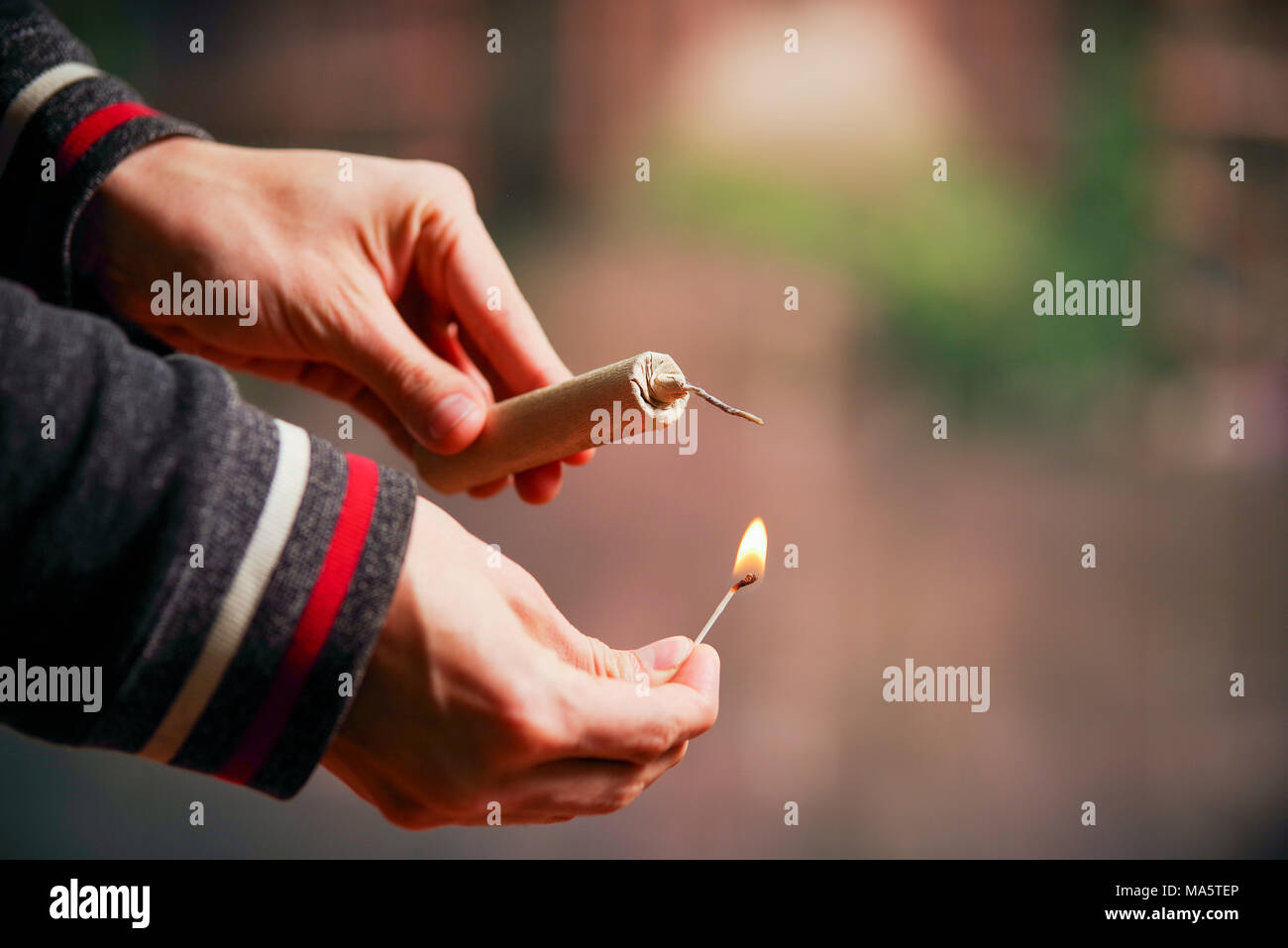 Close up of man hand lighting up a firecrackers in a burred background ...
