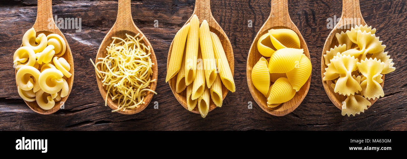 Different pasta types in wooden spoons on the table. Top view Stock ...