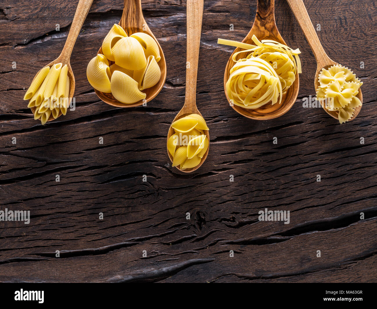 Different pasta types in wooden spoons on the table. Top view Stock ...