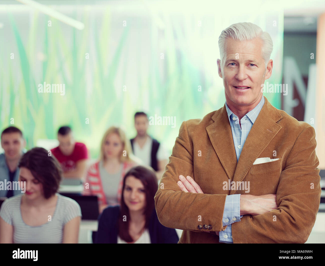 portrait of confident teacher in school classroom, students group on ...