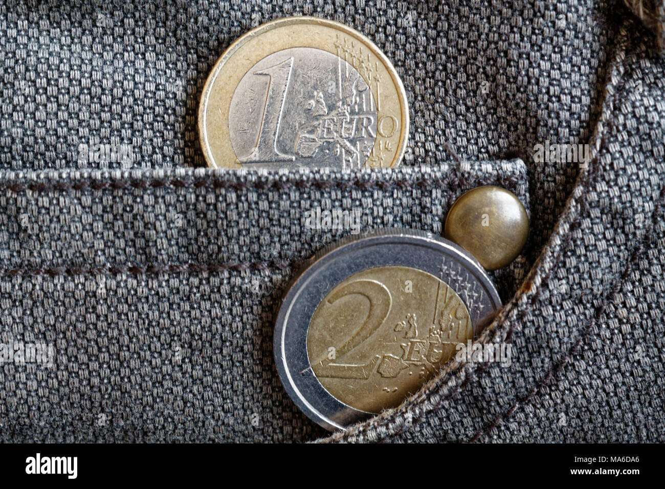 Euro coins with a denomination of one and two euro in the pocket of ...