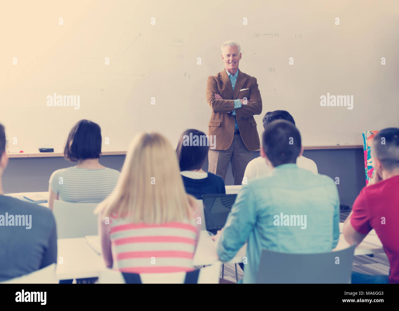 senior teacher with group of happy students in modern school classroom ...