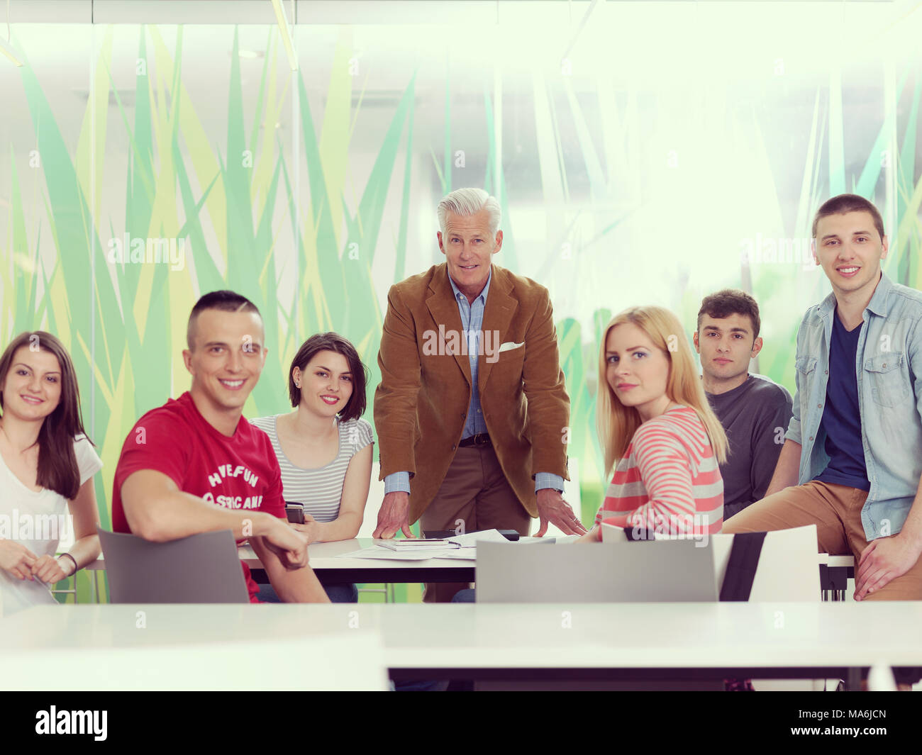 portrait of confident teacher in school classroom, students group on ...