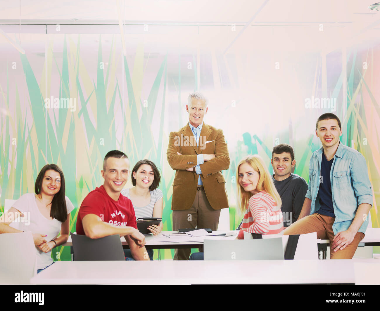 portrait of confident teacher in school classroom, students group on ...