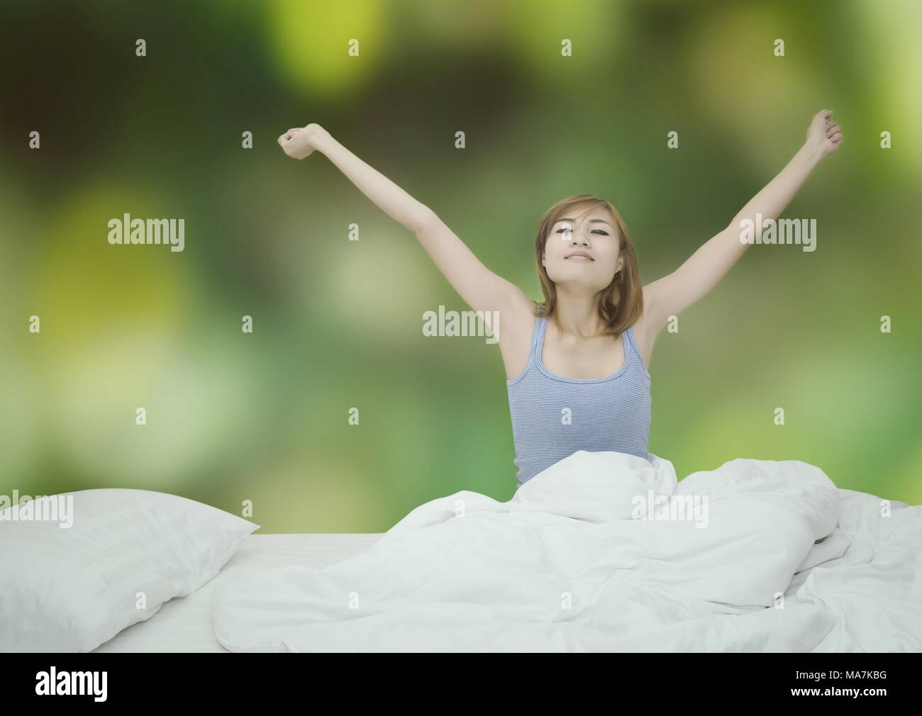 Tired sleepy woman waking up and yawning with a stretch while sitting ...