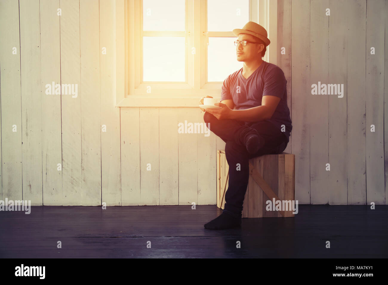 Young handsome man looking out his window at home in the room alone ...