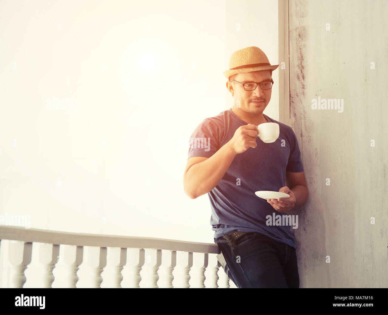 Handsome man standing out of home lean on the balcony drinking coffee ...