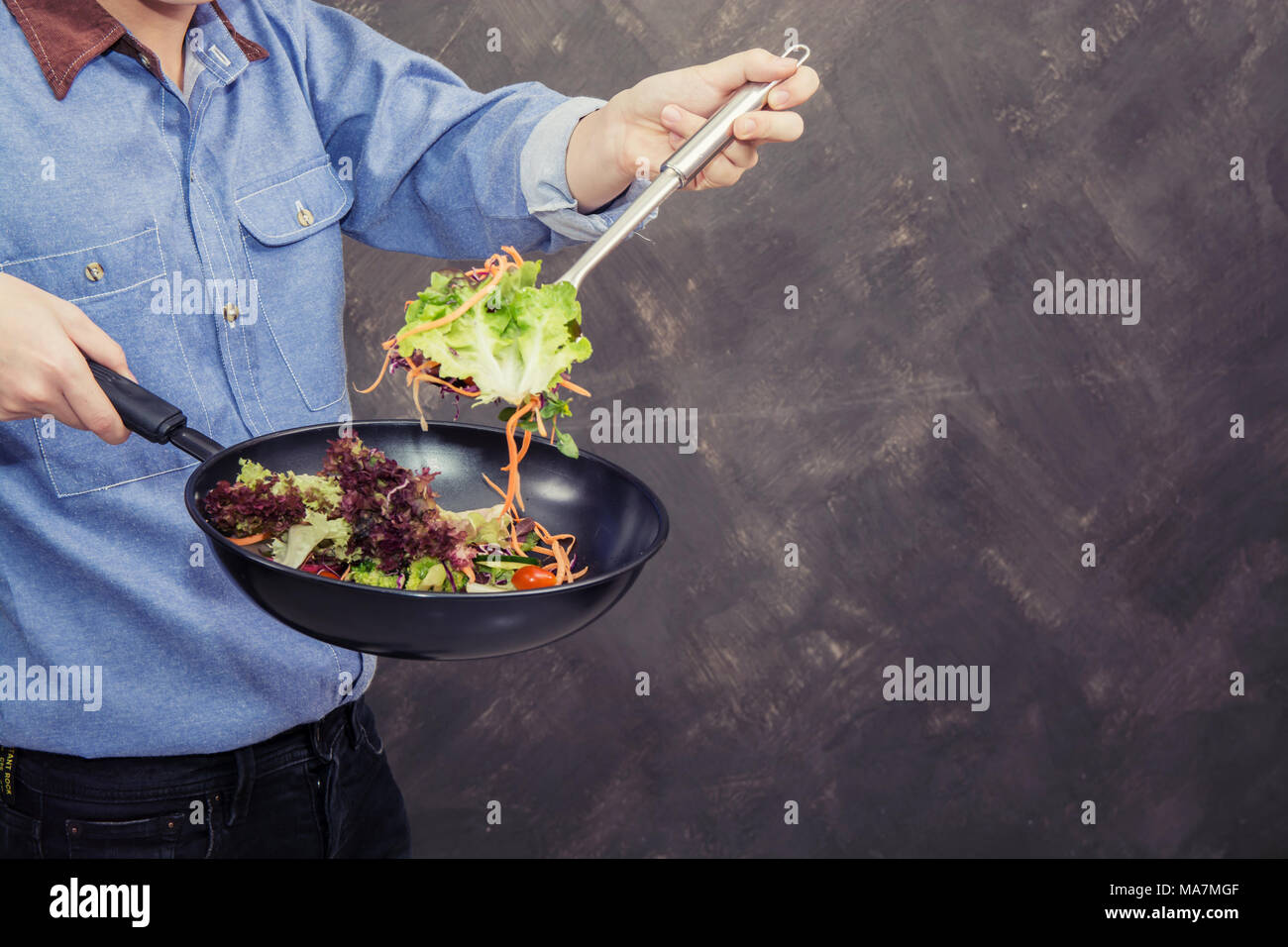 man cooking salad on the pan on grunge background Stock Photo - Alamy