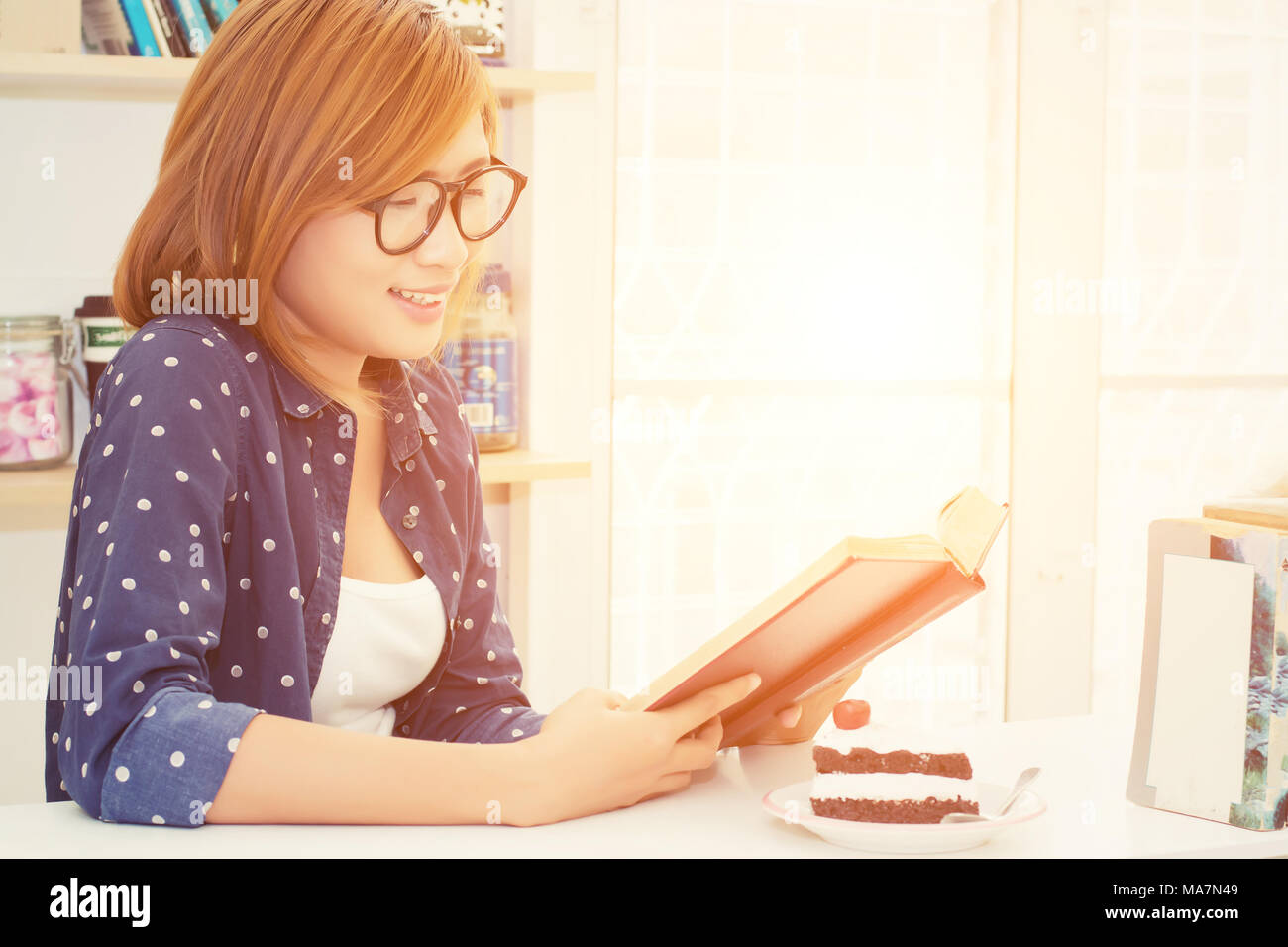 Charming young woman sitting reading book in the cafe Stock Photo - Alamy