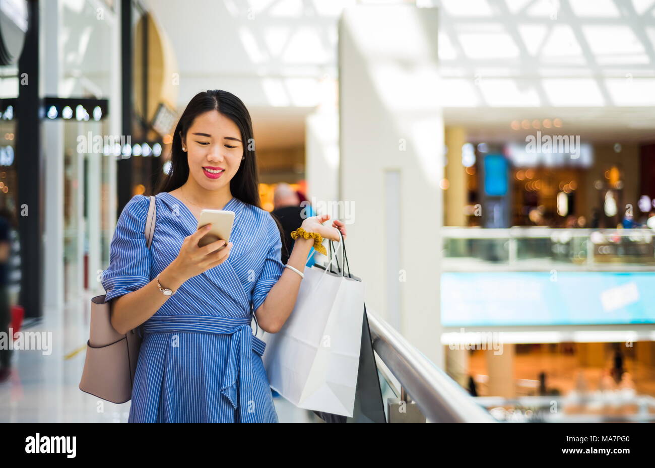 Girl using phone while doing shopping in the mall Stock Photo - Alamy