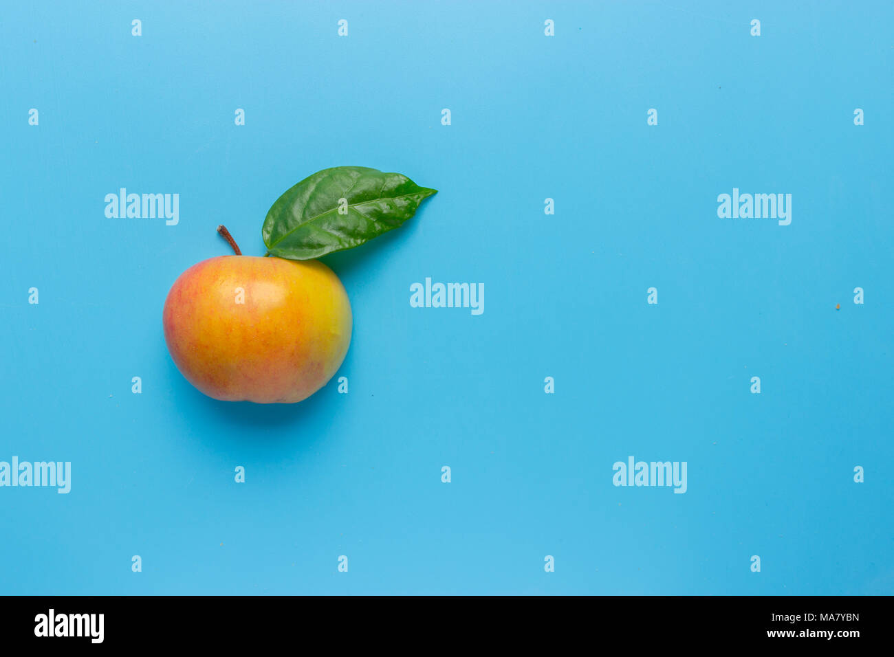 single apple with copy space on blue background Stock Photo - Alamy