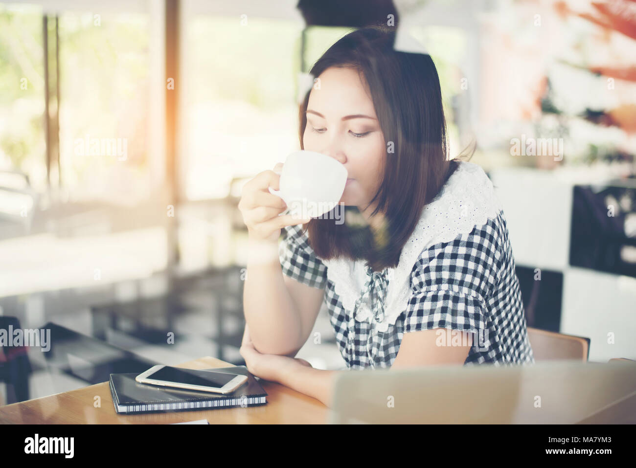 Beautiful woman sitting and drinking coffee at cafe Stock Photo - Alamy