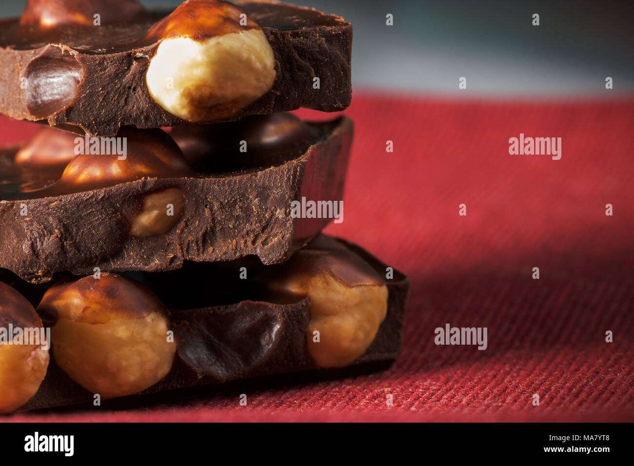 Slices of natural black chocolate with hazelnuts on a red napkin. Close ...