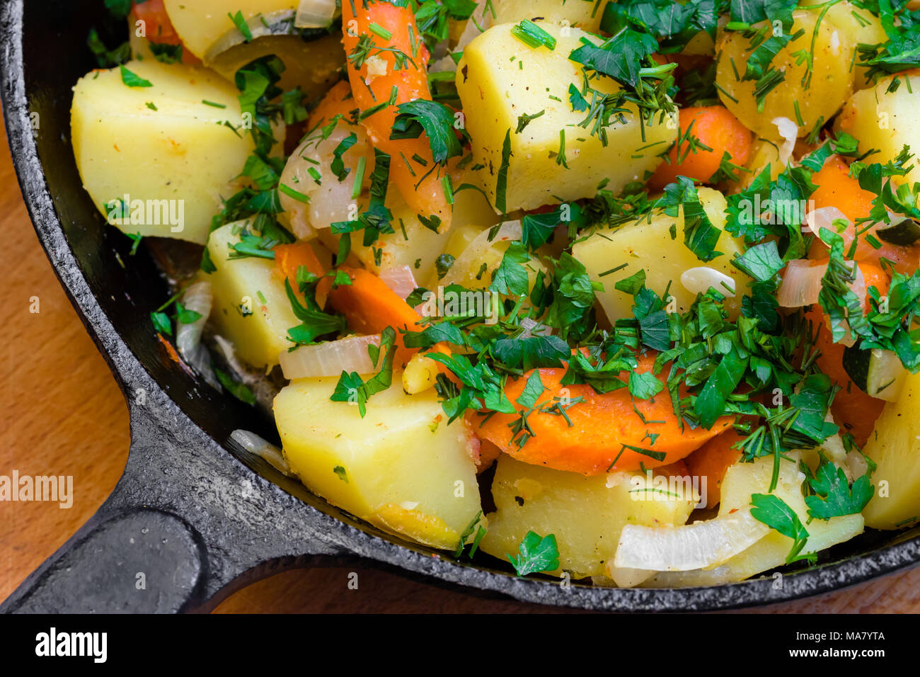 Fried potatoes with vegetables sprinkled with chopped parsley in a cast ...