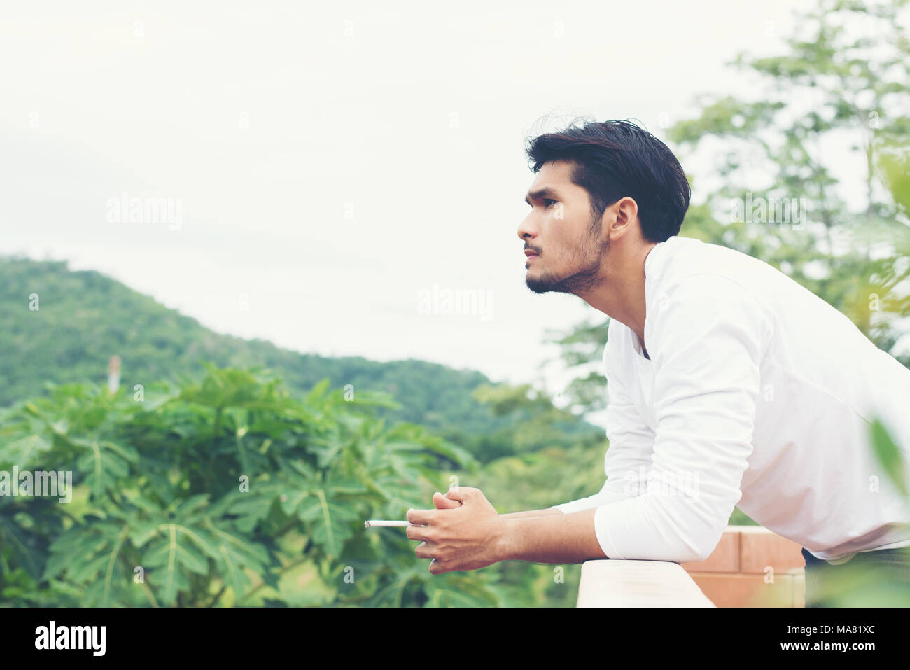 Young hipster man taking rest, smoking cigarette with nature and fresh ...