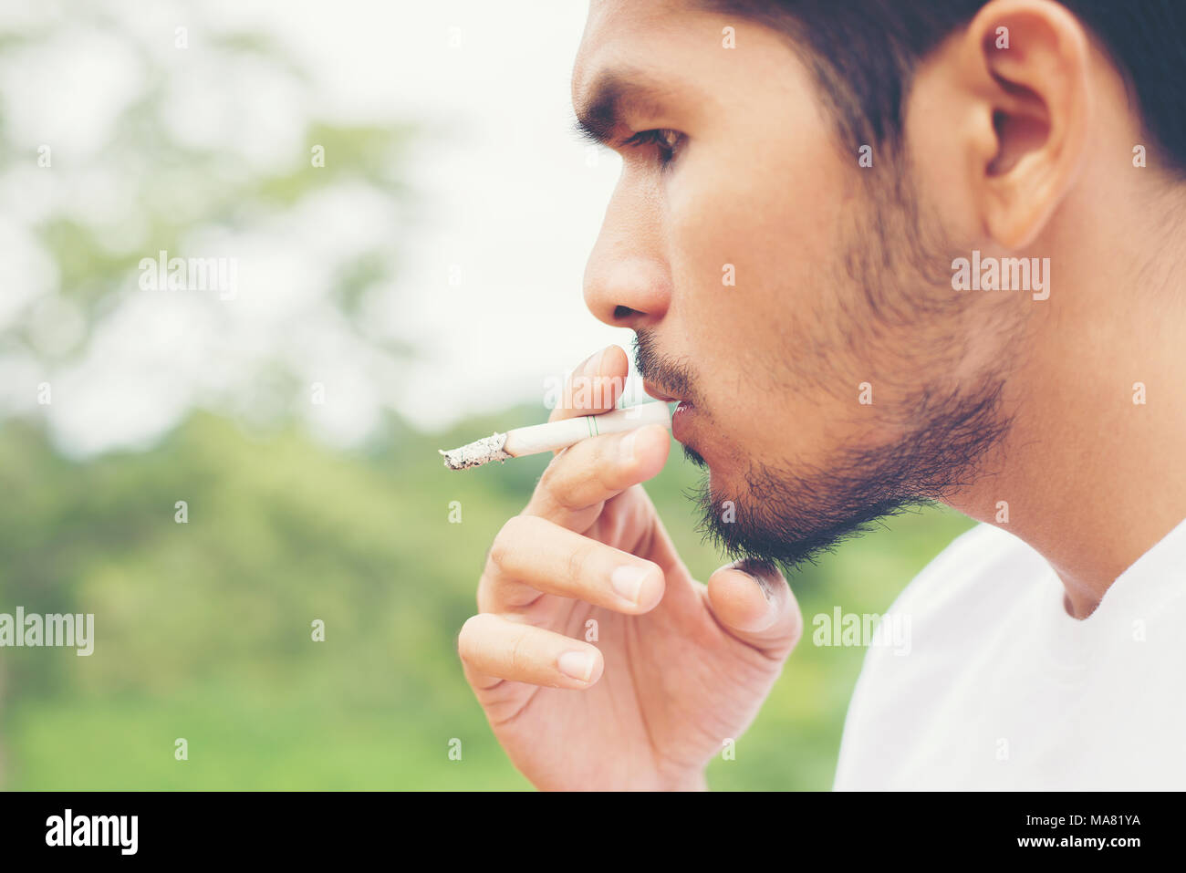 Young hipster man taking rest, smoking cigarette with nature and fresh ...