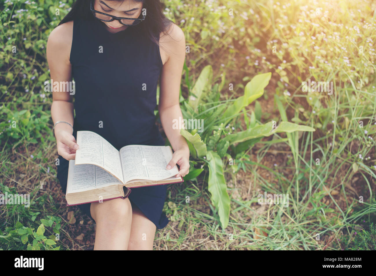 Relaxed young beautiful woman reading a book at the lawn with sun ...