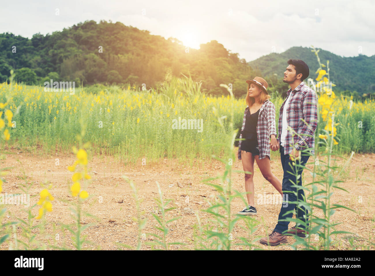 Young hipster couple taking a walk on beautiful flower field Stock ...