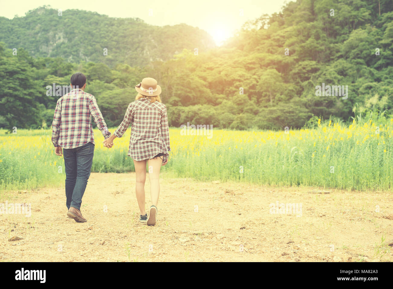 Young hipster couple taking a walk on beautiful flower field Stock ...