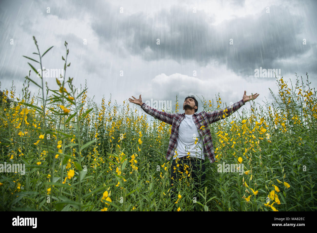 Handsome hipster man standing raising hands in the air in a yellow ...