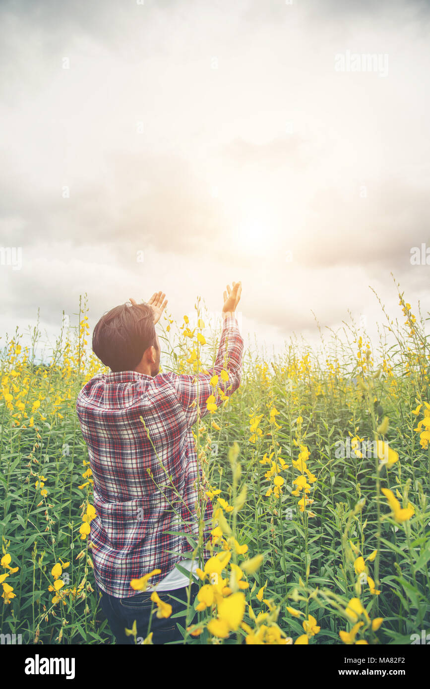 praying man standing in yellow flower field on mountain view background ...