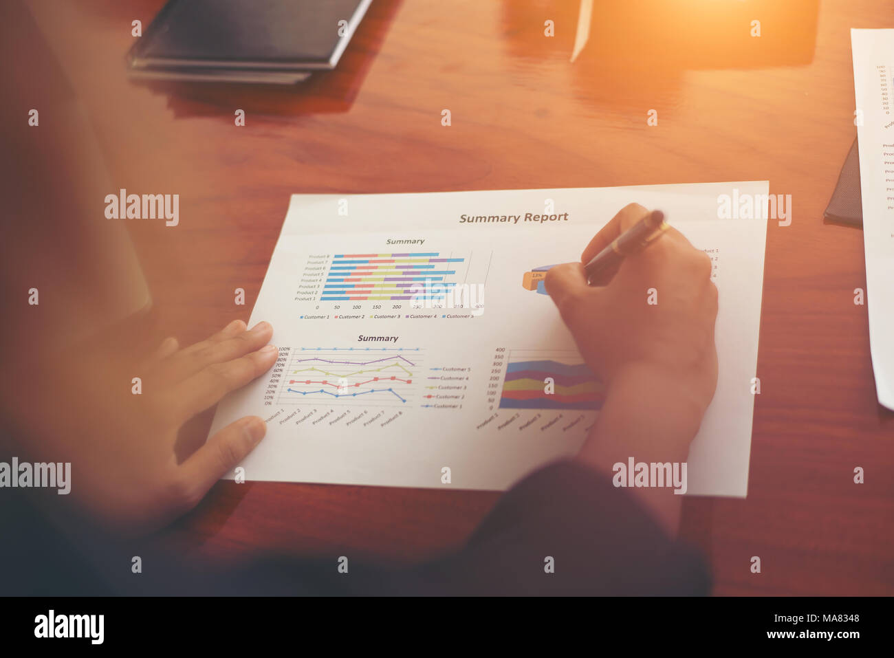 Woman's hand with a pen writing on the business paper. Report chart ...