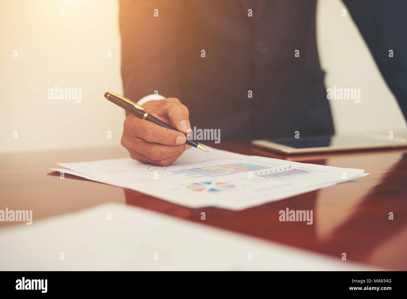 Woman's hand with a pen writing on the business paper. Report chart ...