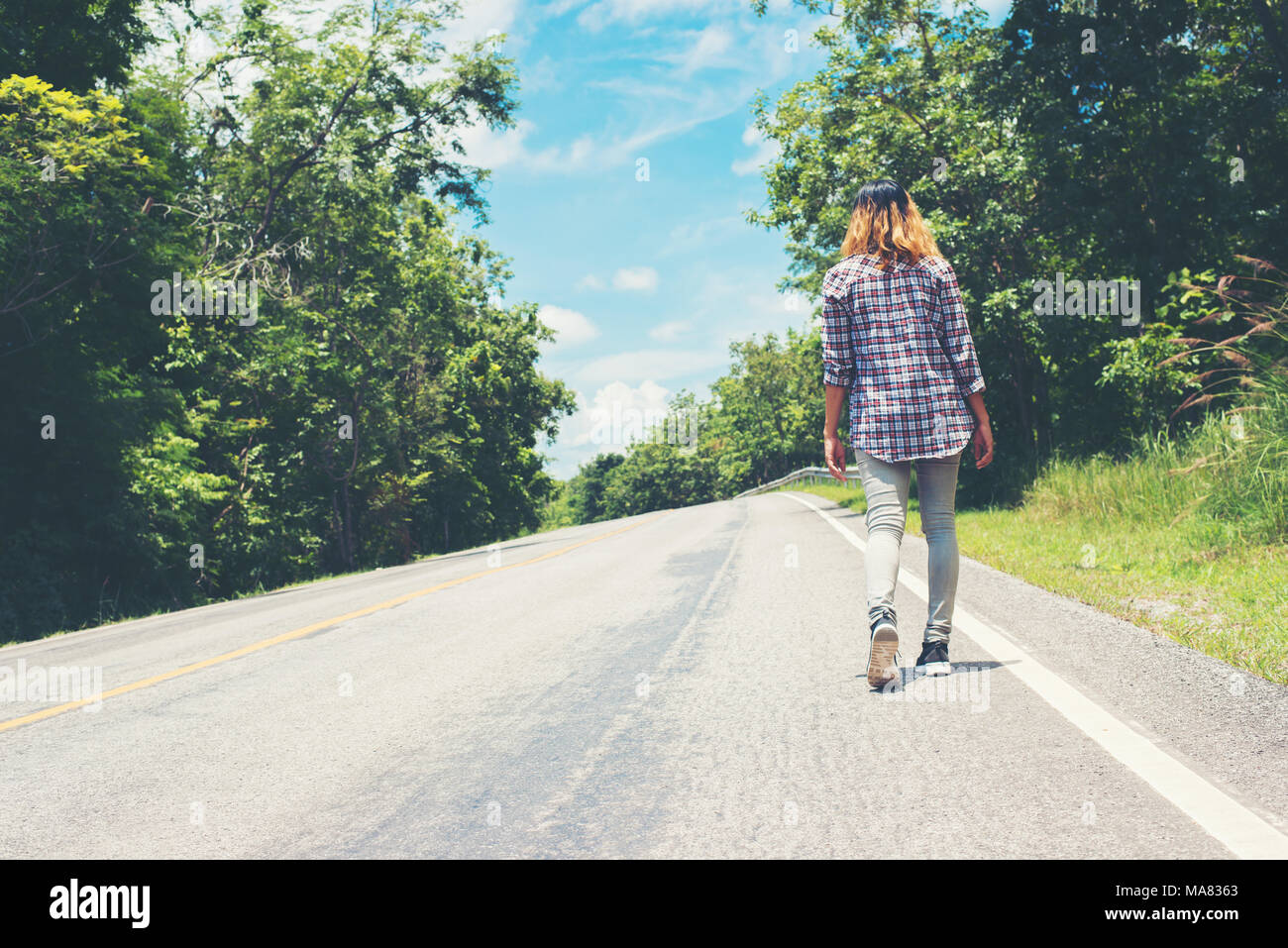 Young hipster woman walking away on side road alone Stock Photo - Alamy