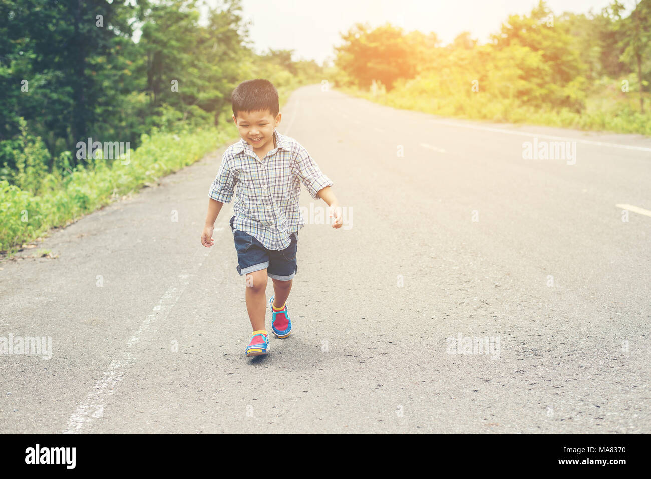 Happy little boy in motion, smiley running on the street Stock Photo ...