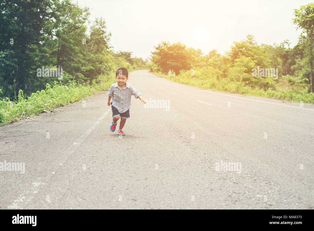 Happy little boy in motion, smiley running on the street Stock Photo ...