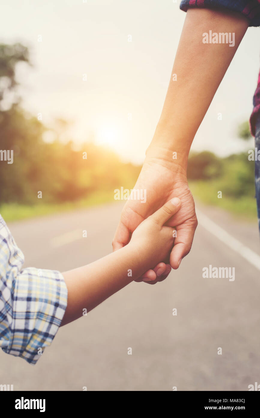Mother holding hand of her son outdoors in summer walking on the ...