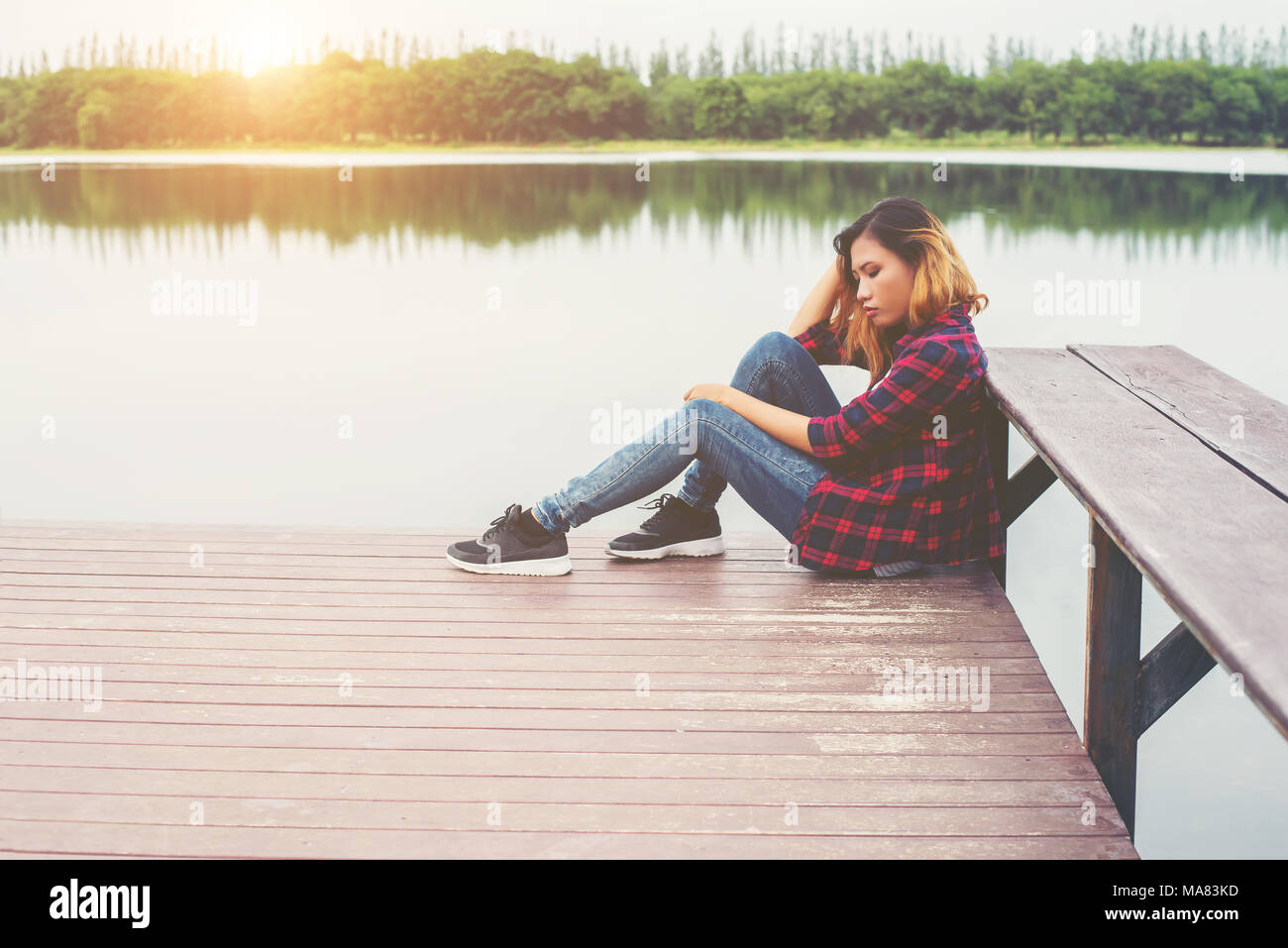 Sad hipster woman sitting on the pier with sadness Stock Photo - Alamy