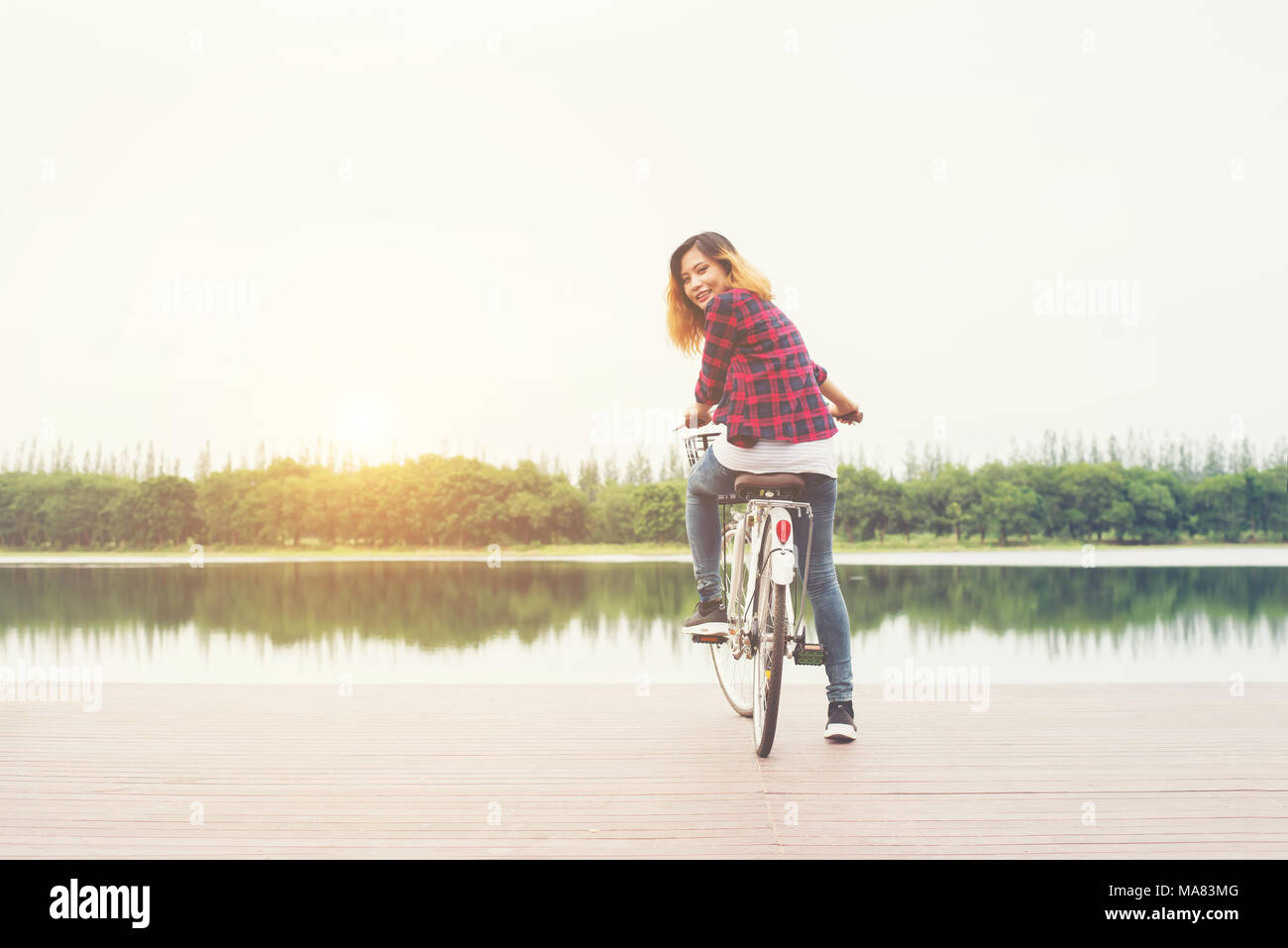 Woman feet pedal bike on the wooden bridge looking back at camera ...