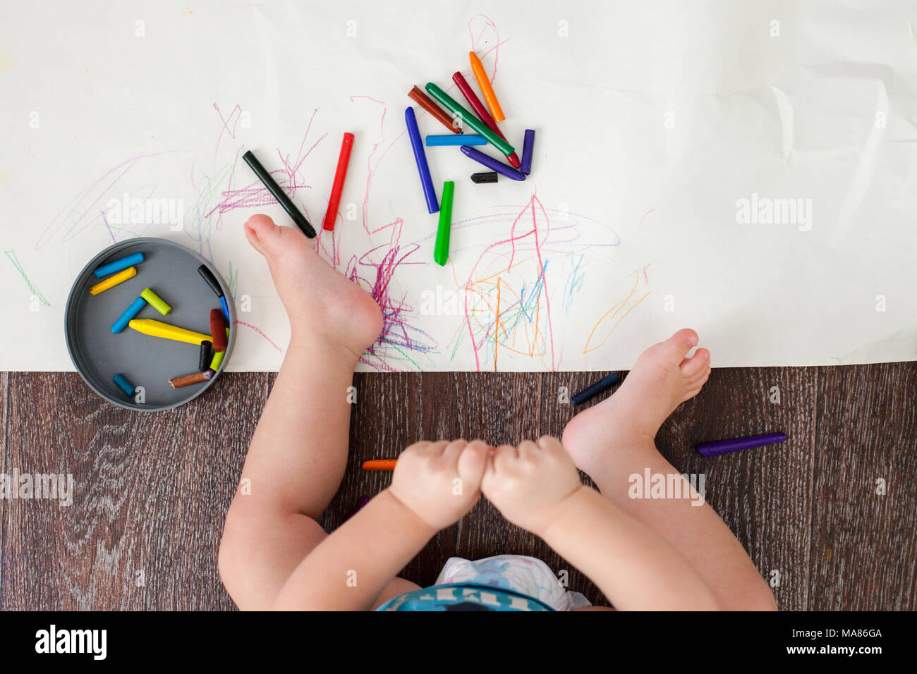 the child draws wax crayons on the floor Stock Photo - Alamy