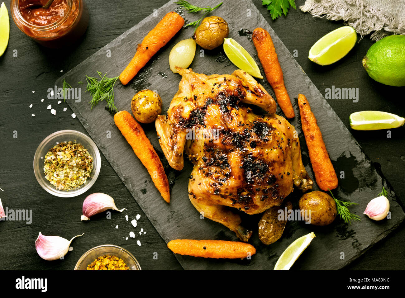 Grilled chicken with vegetables over black stone background. Top view ...